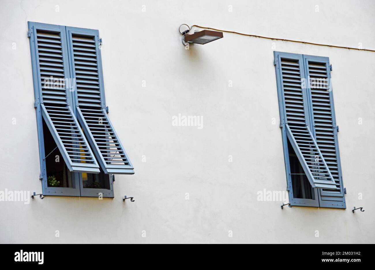Two windows with blue shutters and an electric lantern on the facade of ...