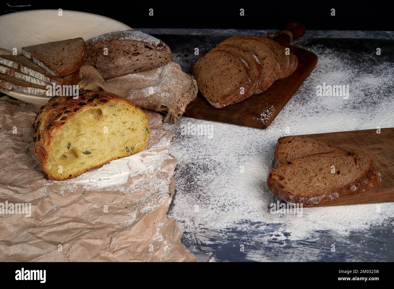 Different types of sliced bread and a loaf on a wooden background ...