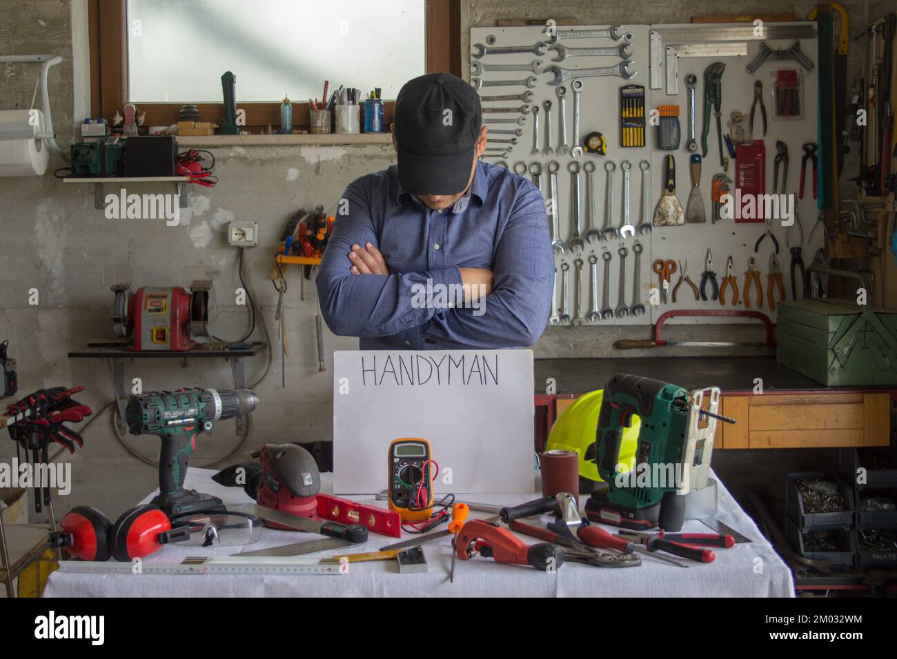 Image of a smiling man in his workshop with a bench full of work tools ...