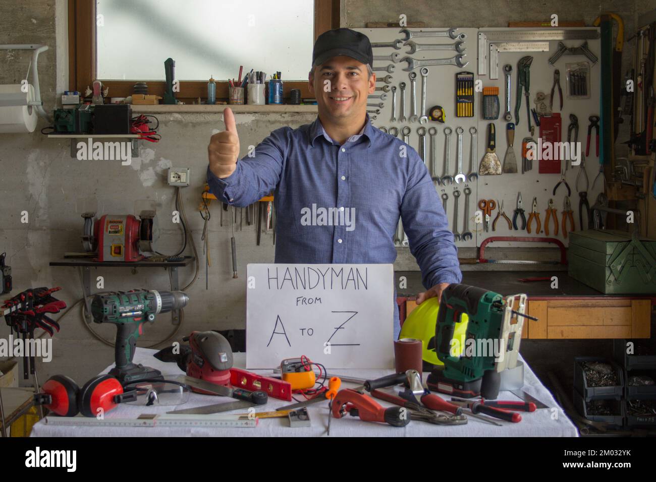 Image of a smiling man in his workshop with a thumbs up behind a bench ...