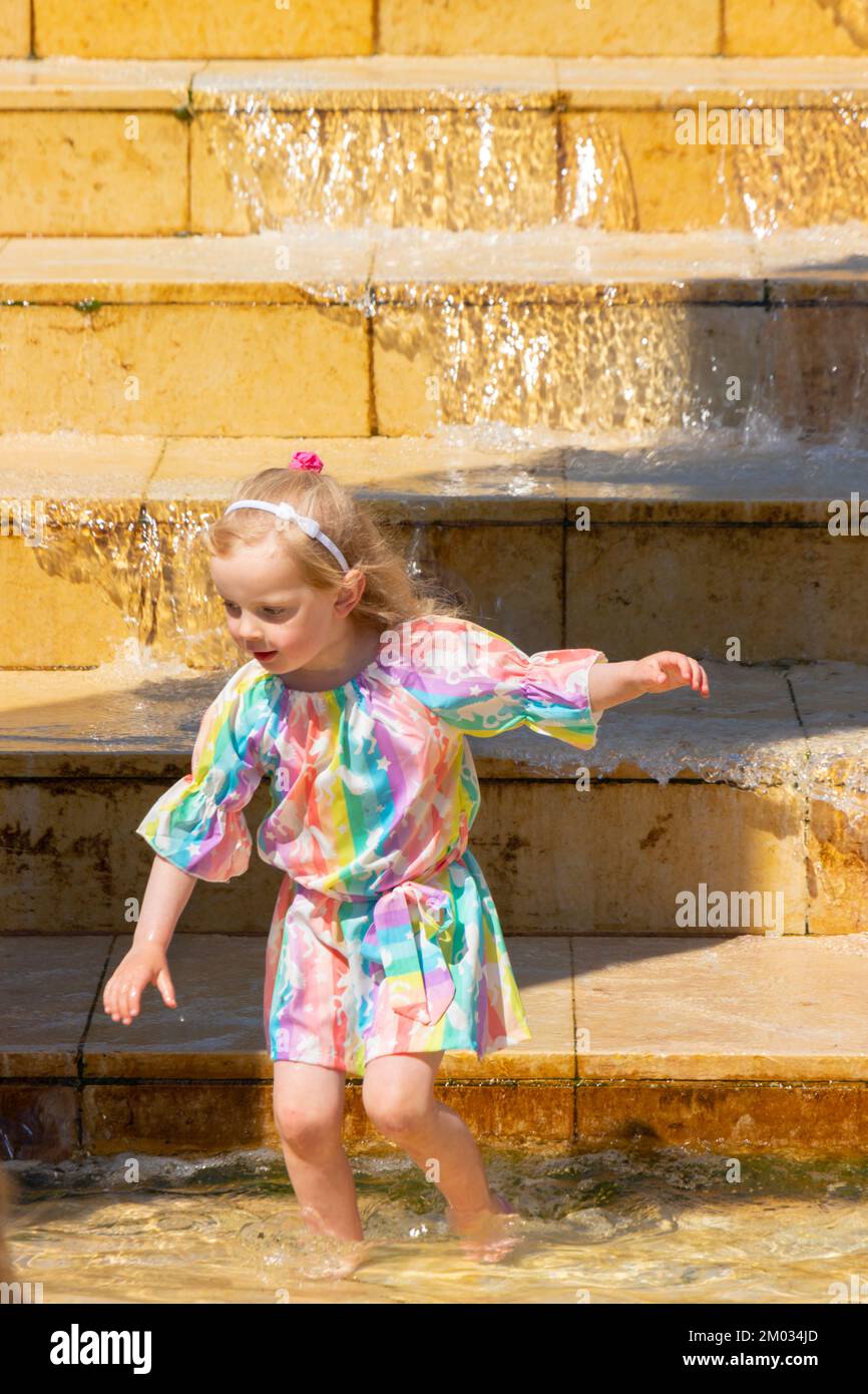 young girl playing in the water of cascade steps in bristol city centre ...