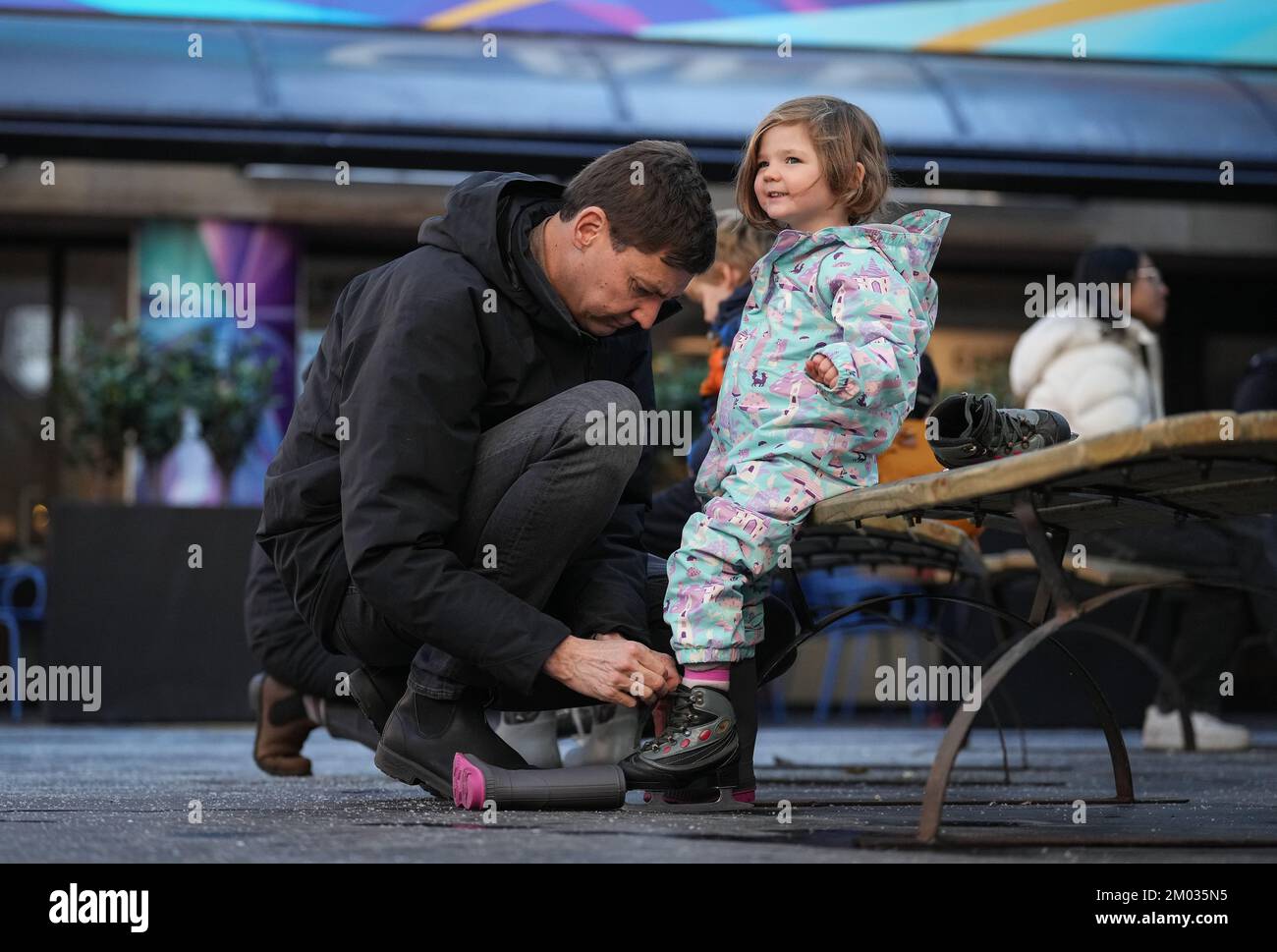 B.C. Premier David Eby ties his three-year-old daughter Iva's skates as ...