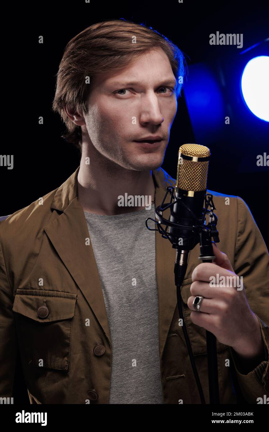 A young man is singing with a microphone in his hands in the stage ...