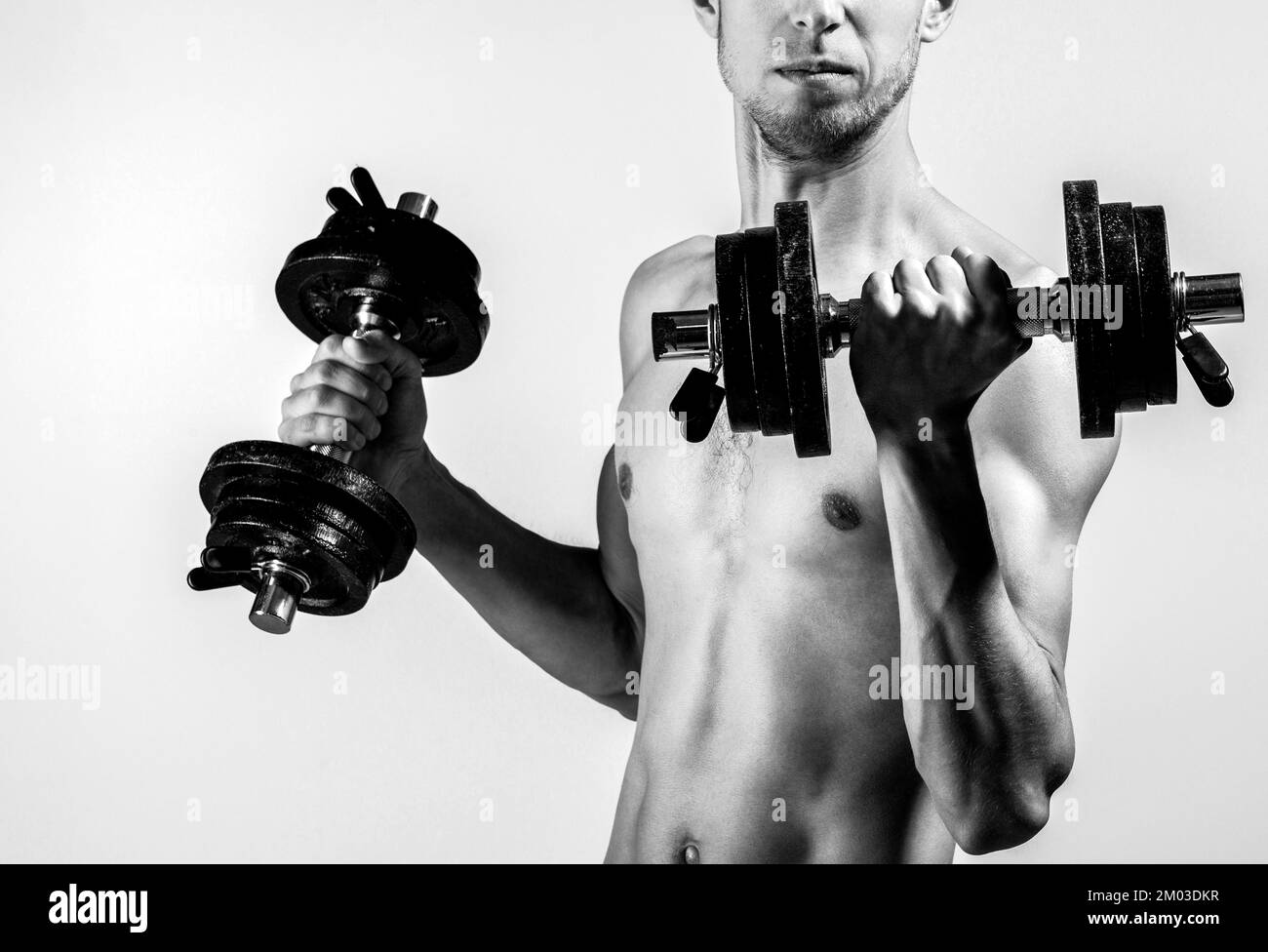 A thin man in sports with dumbbells. Weak man lift a weight, dumbbells ...