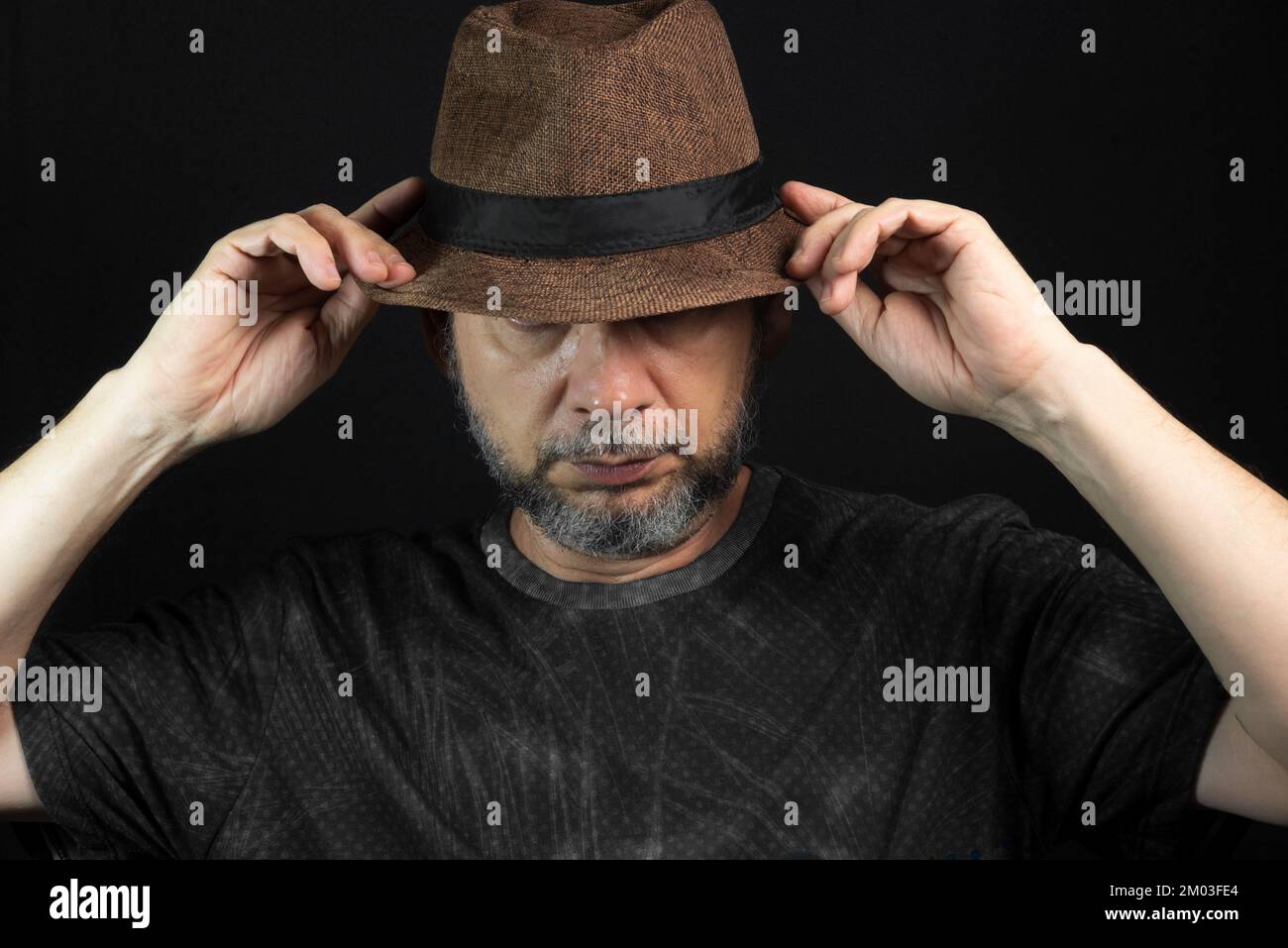 Beard man. With both hands holding the hat. Isolated on black ...