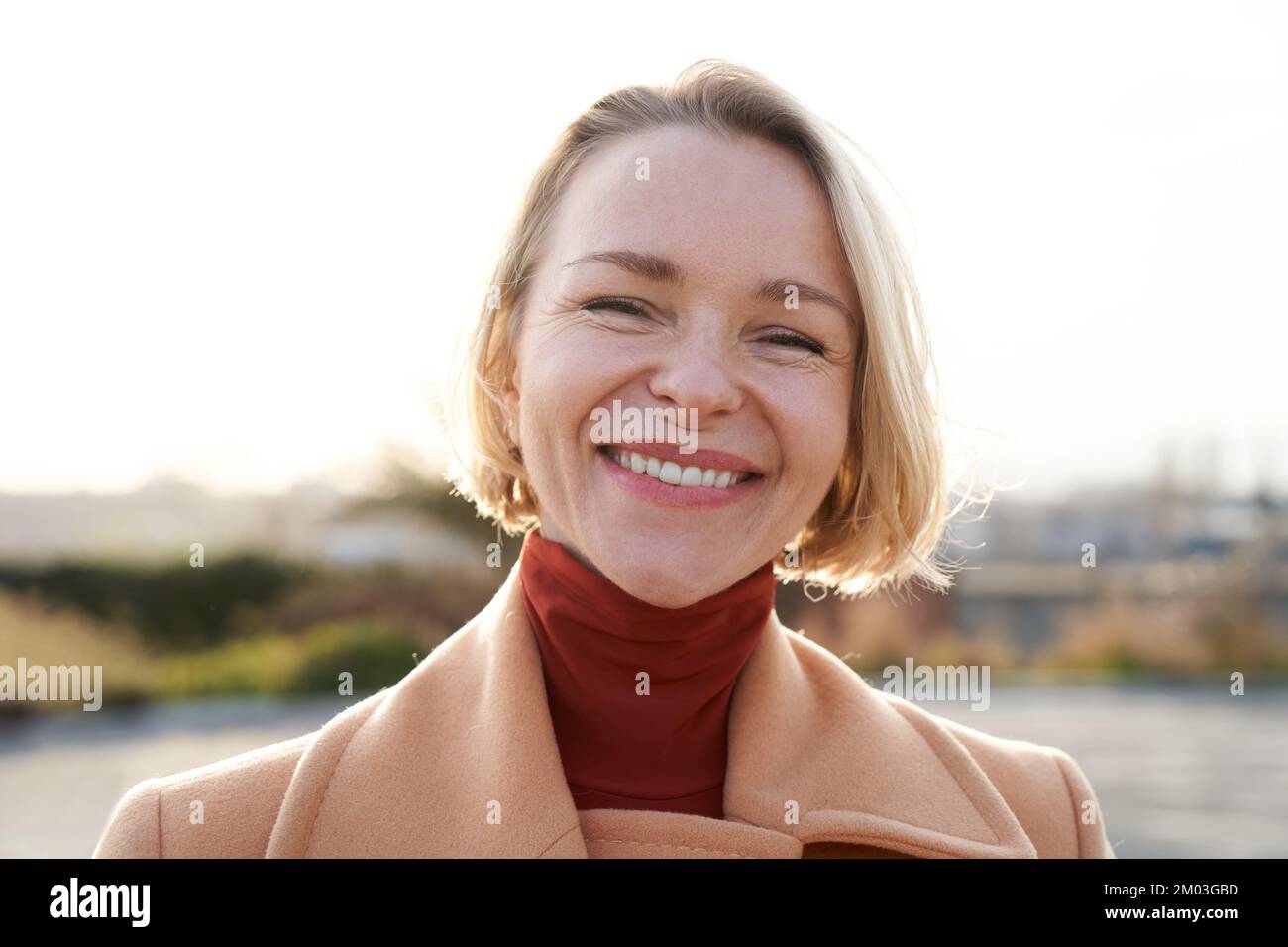 Happy mature Lady in the sunset looking up and turning to camera ...