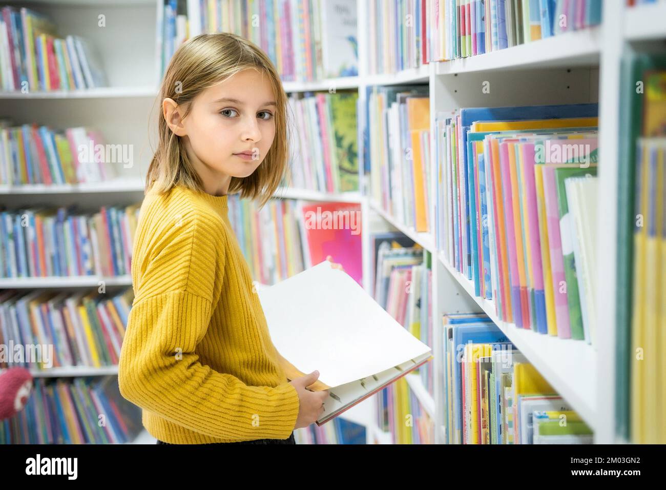 Schoolgirl choosing book in school library Stock Photo - Alamy