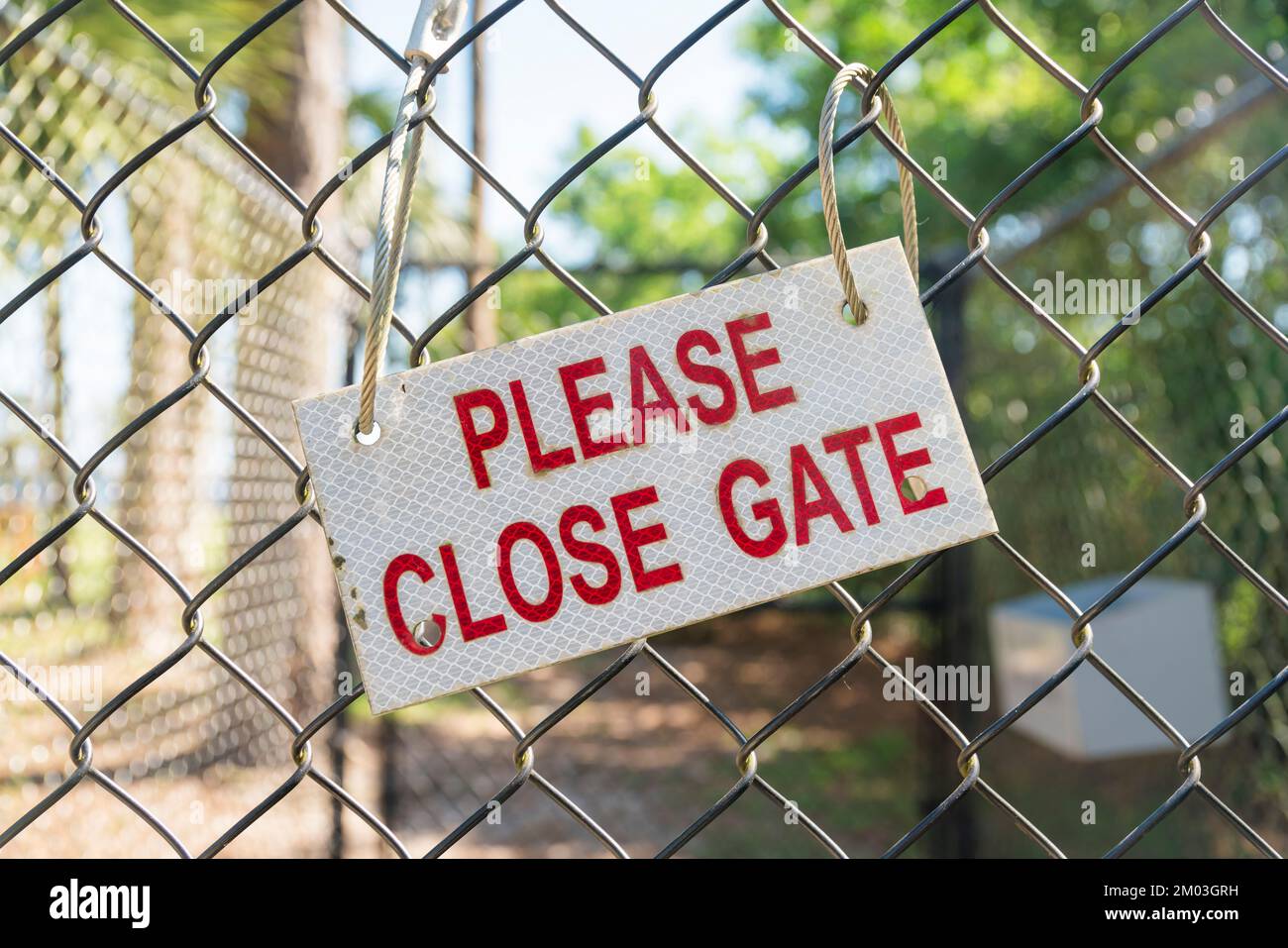 Sign with Please Close Gate hanged with a rope on a chain link fence ...