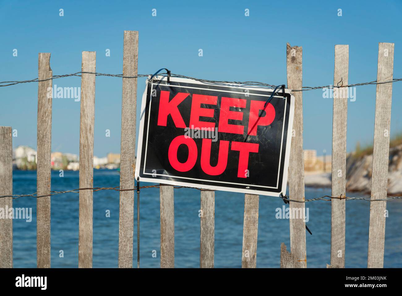Red and black Keep Out sign on a wire and wood slat fence at Destin ...