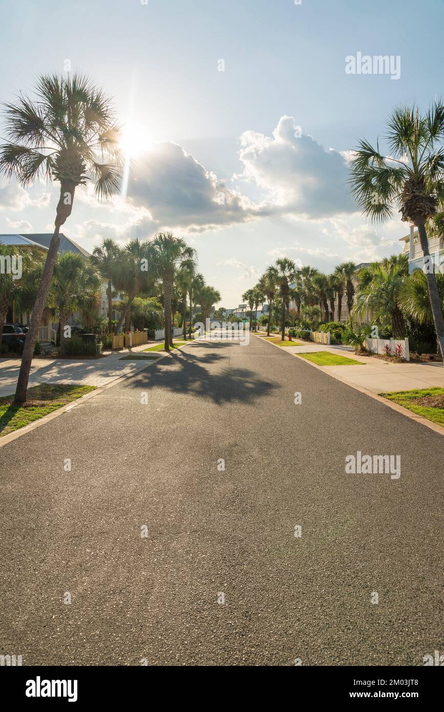 Sun behind the clouds above the asphalt street in a residential area at ...