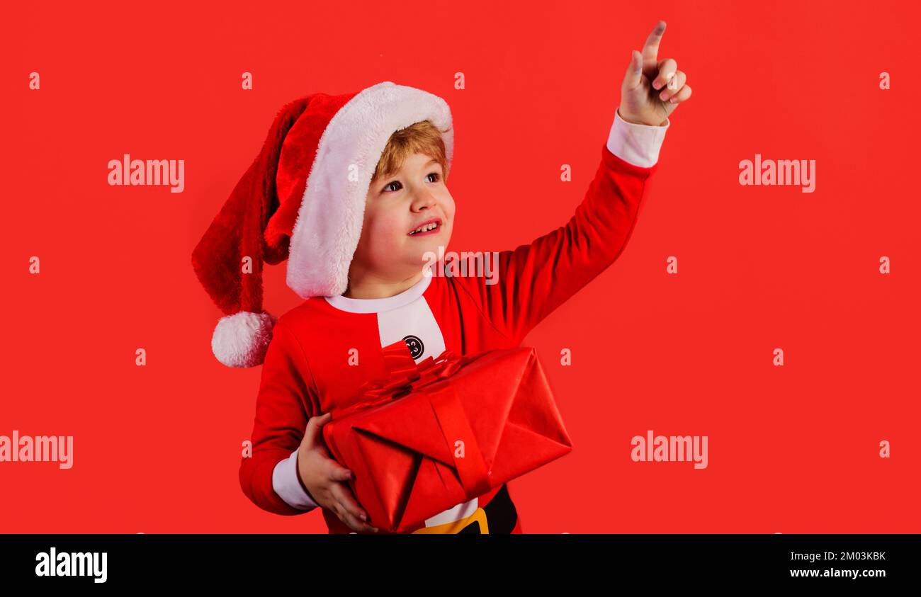 Santa helper. Little child boy in Christmas hat with present gift box ...