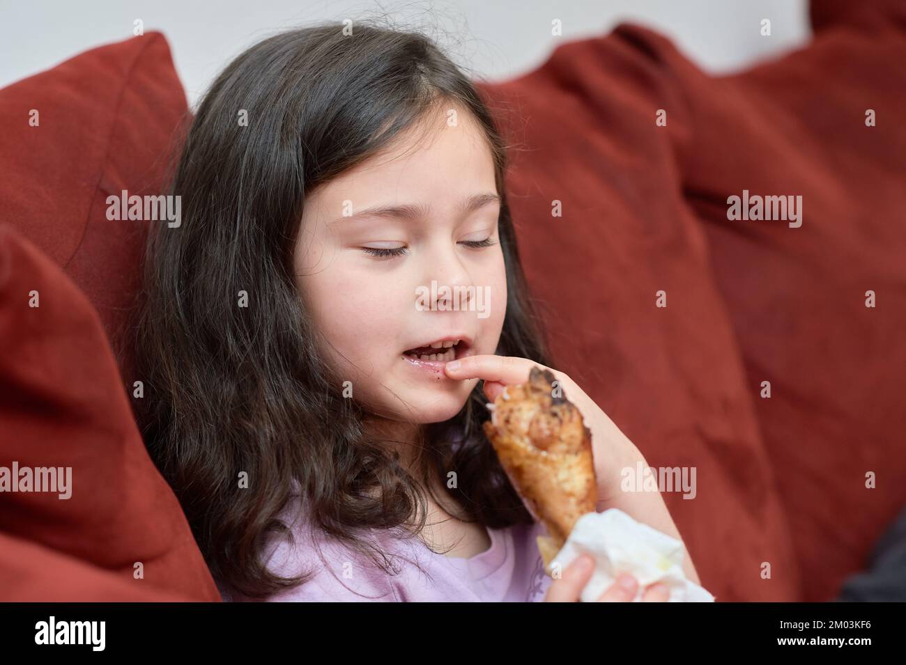 expressive young girl is eating chicken and vegetables for dinner on ...