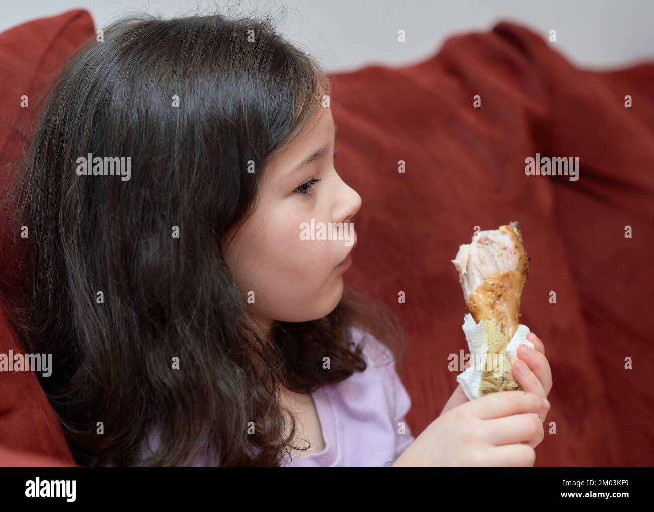 expressive young girl is eating chicken and vegetables for dinner on ...