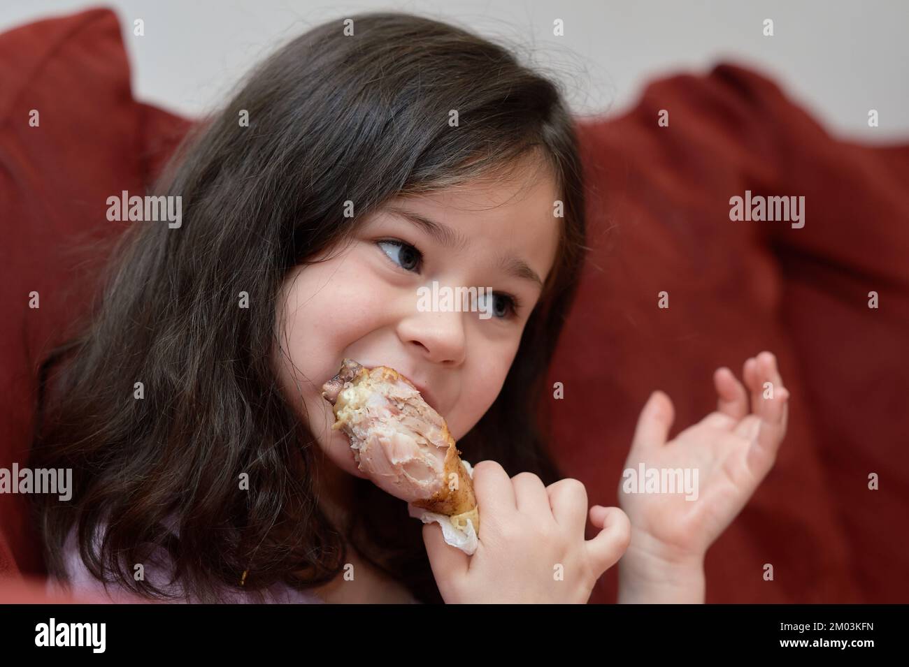 expressive young girl is eating chicken and vegetables for dinner on ...