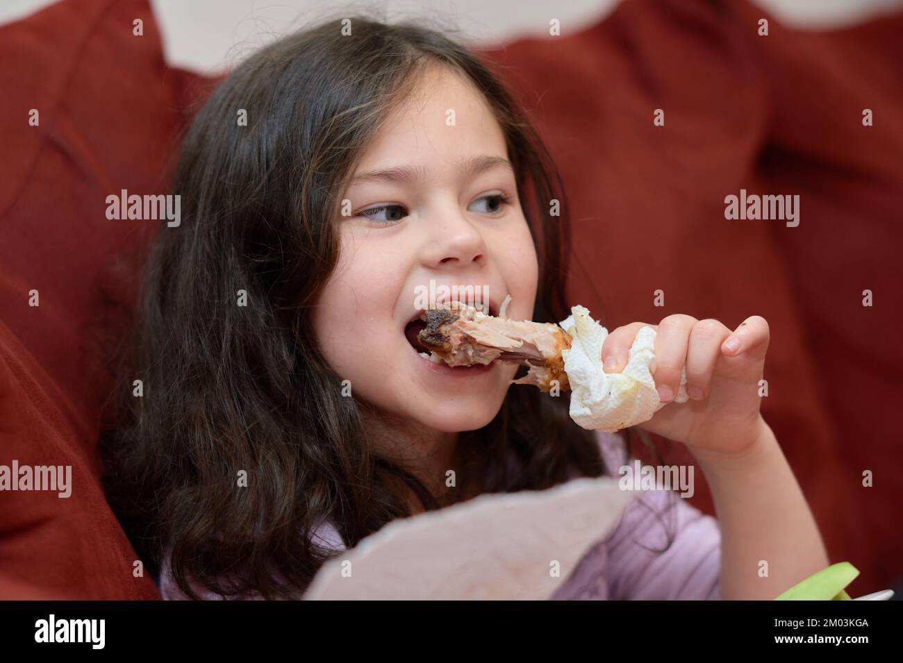 expressive young girl is eating chicken and vegetables for dinner on ...