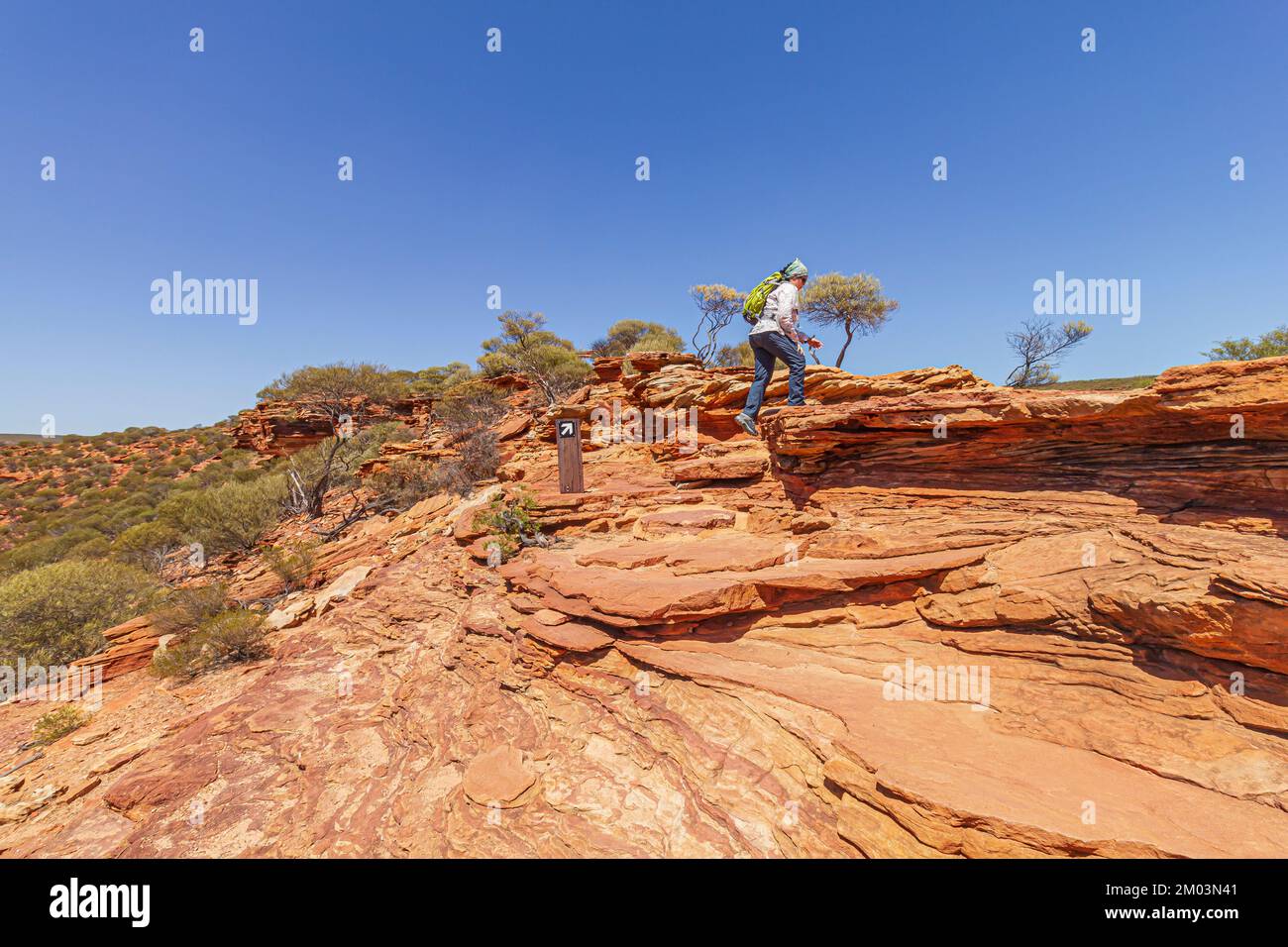 Lone woman hiker scrambling up on sandstone rock surface of Nature ...