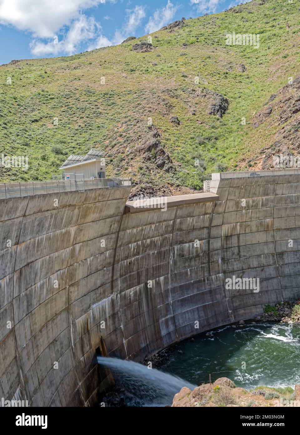 A stream of water spouts out of the concrete wall of the Wild Horse Dam ...