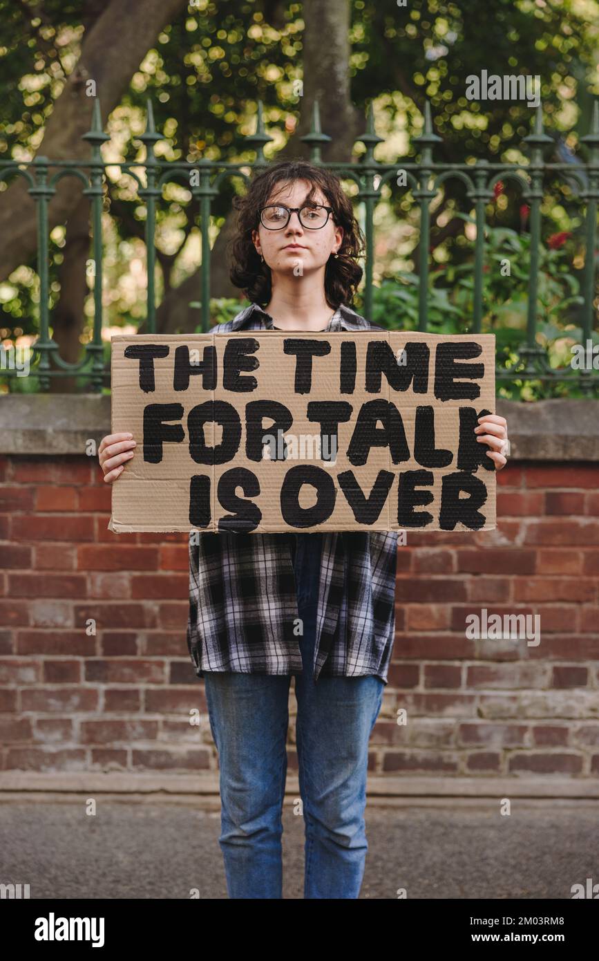 Teenage activist looking at the camera while holding a poster ...