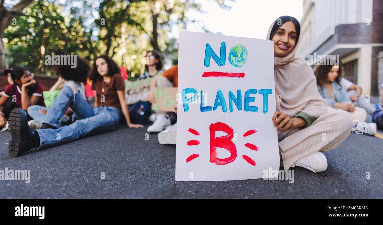 Happy Muslim girl holding a "No planet B" poster at a climate change ...