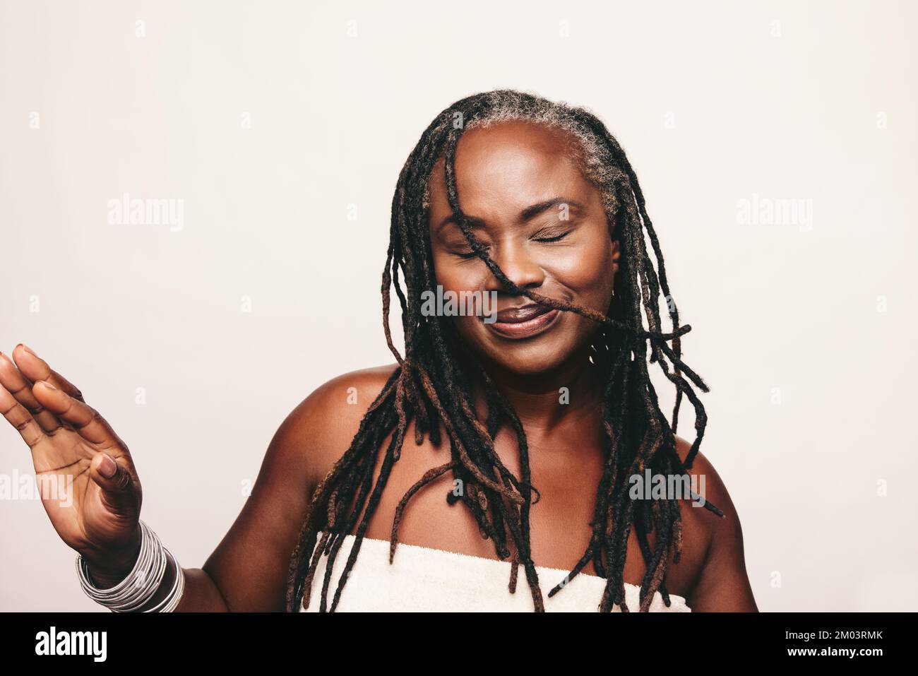 Happy woman with dreadlocks wearing a bath towel and make-up in a ...