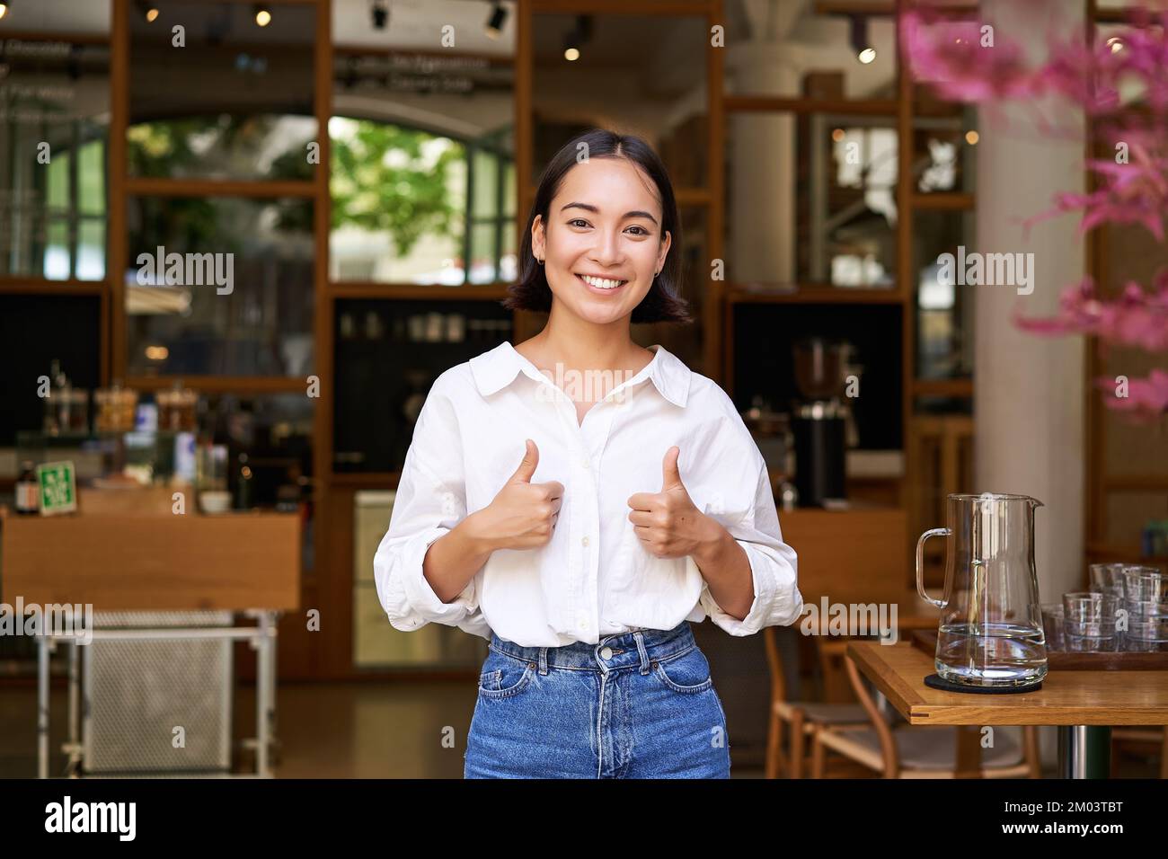 Happy asian woman shows thumbs up, approves, likes smth good, stands ...