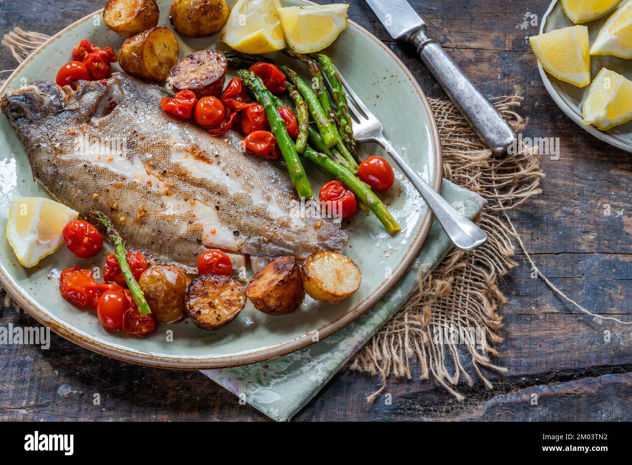 Lemon sole baked with potatoes, baby tomatoes and asparagus Stock Photo ...