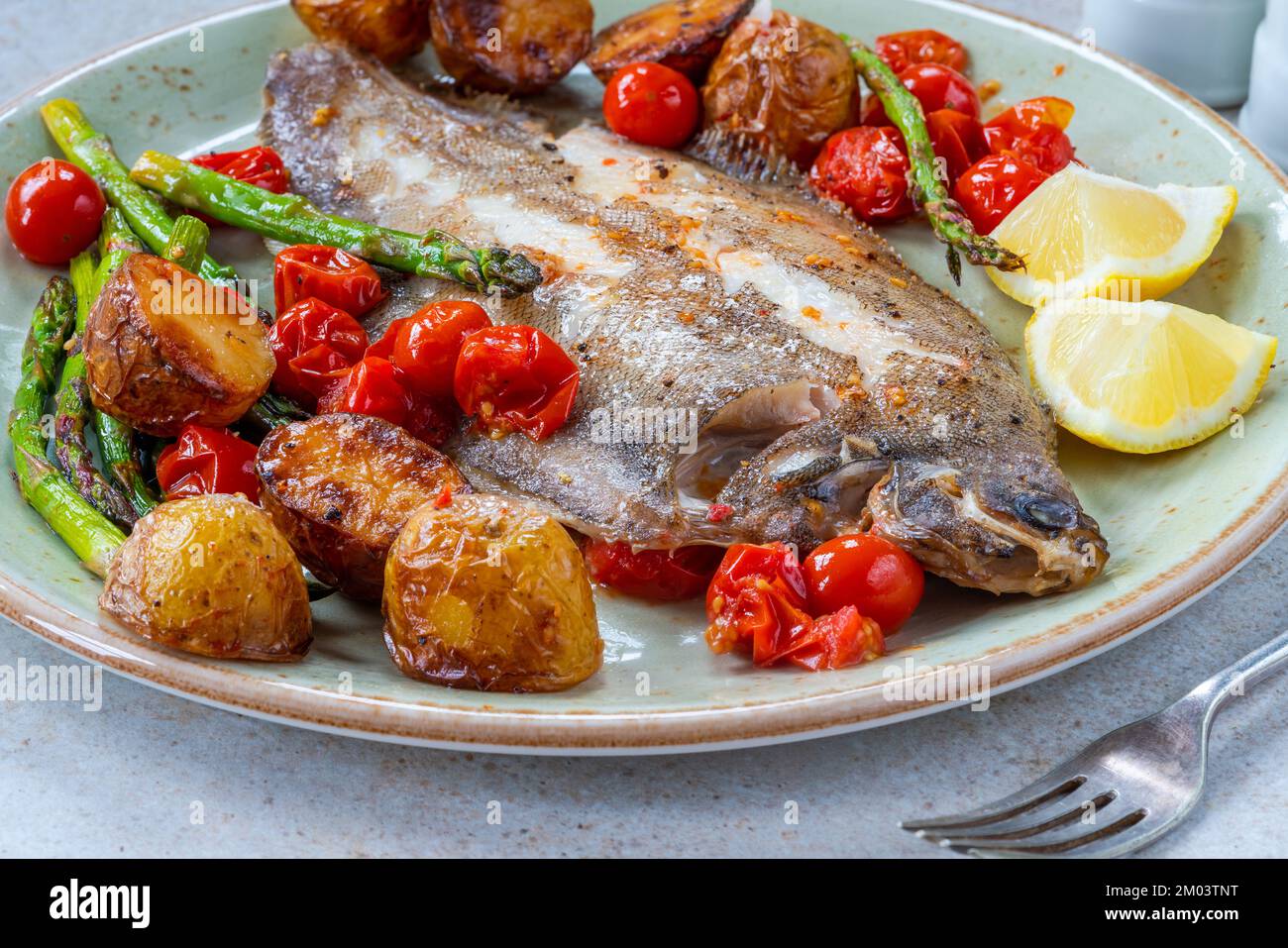 Lemon sole baked with potatoes, baby tomatoes and asparagus Stock Photo ...