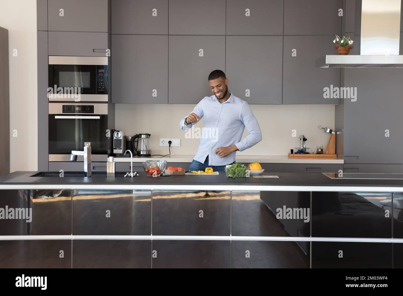 Joyful Black cook blogger dancing to music at kitchen table Stock Photo ...