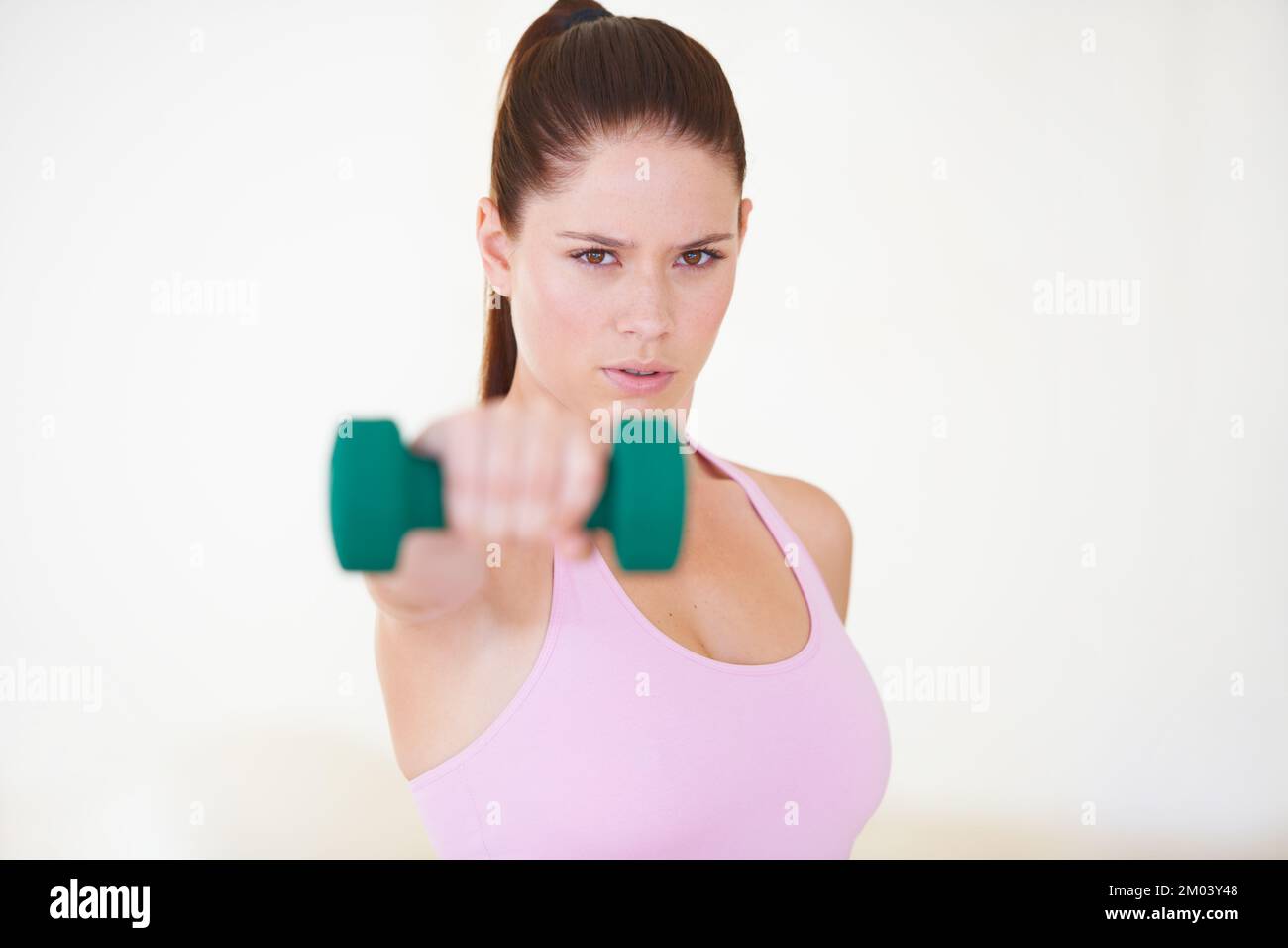 Lifting her way to physical fitness. Portrait of a serious-looking ...