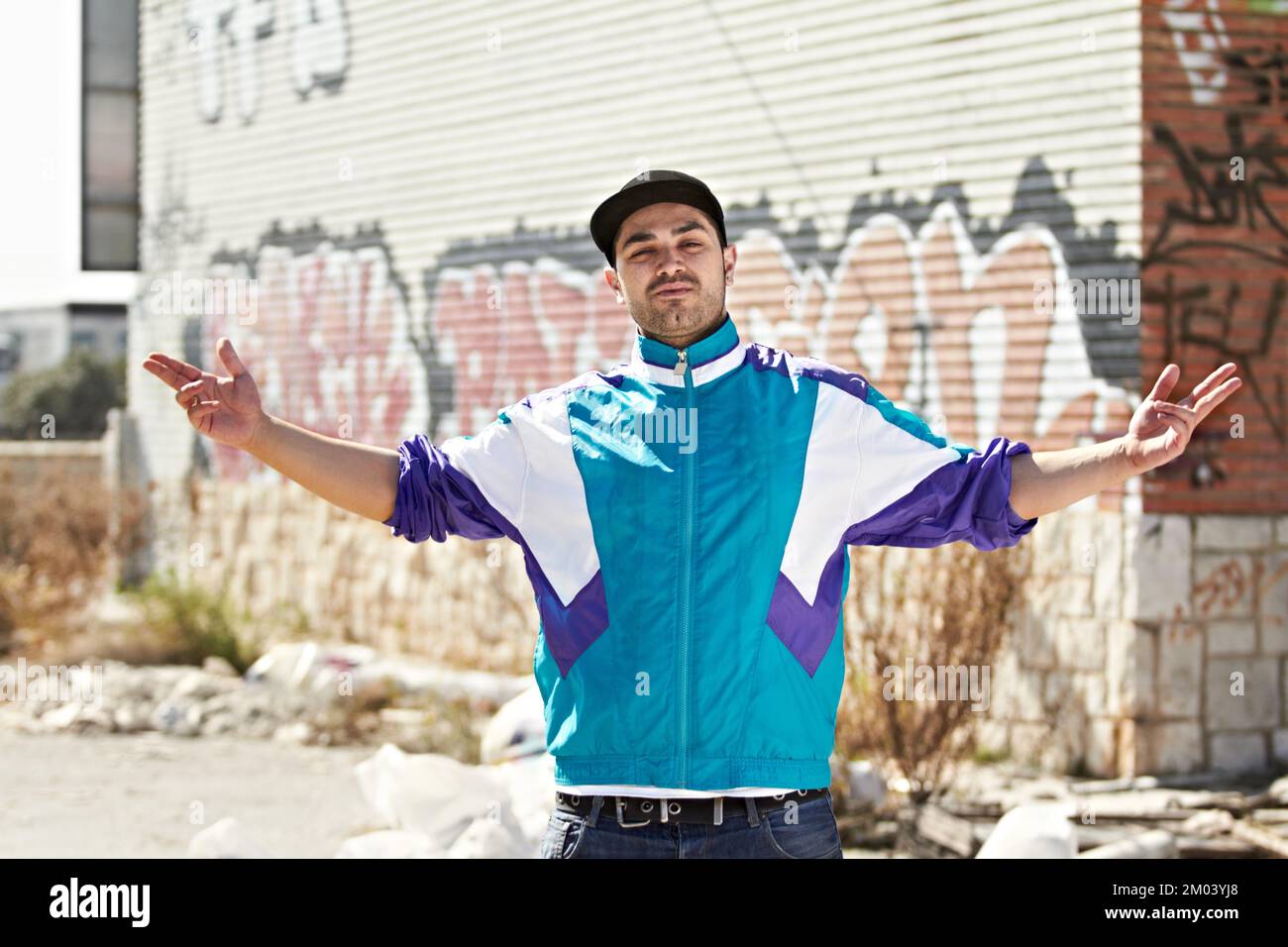 Cool and with attitude. A gangster standing in front of a graffiti wall ...