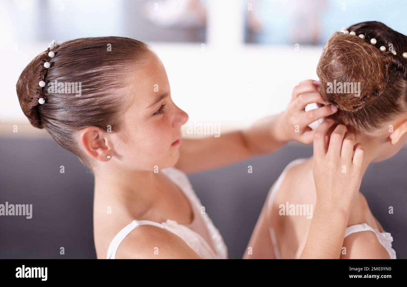 Making sure everyone looks perfect. young ballerina helping adjust her ...