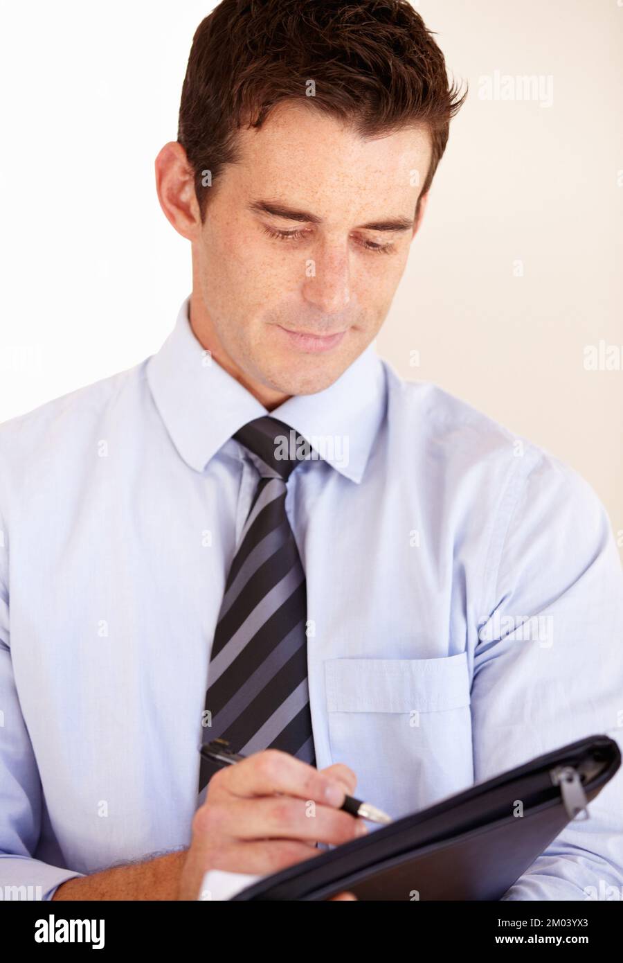 Keeping track of important information. Handsome businessman taking ...