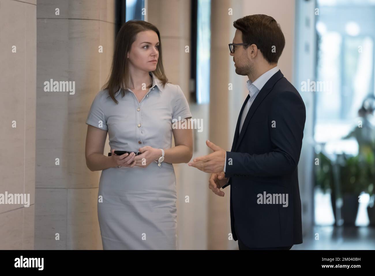 Two colleagues talking meet in modern office hallway Stock Photo - Alamy