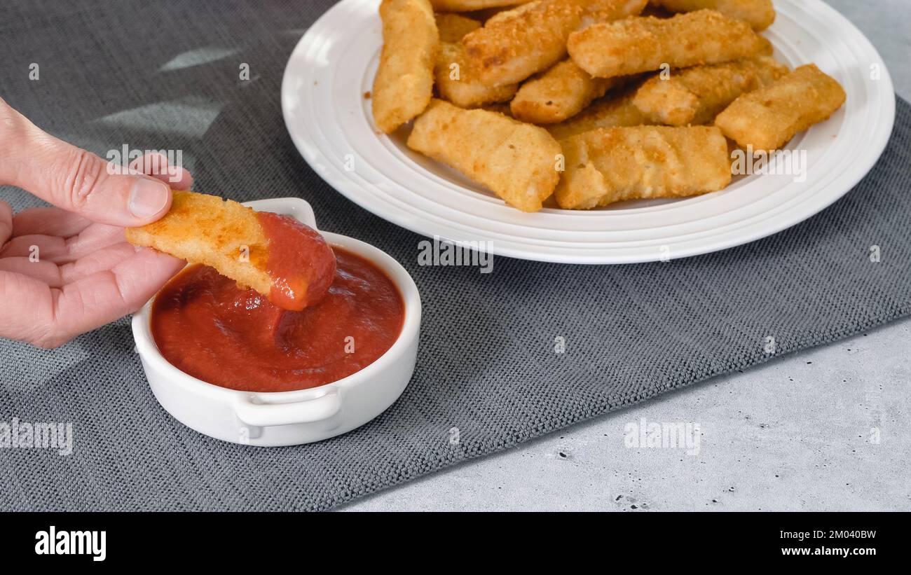 Fish sticks in a crunchy golden breading and bowl of ketchup close-up ...