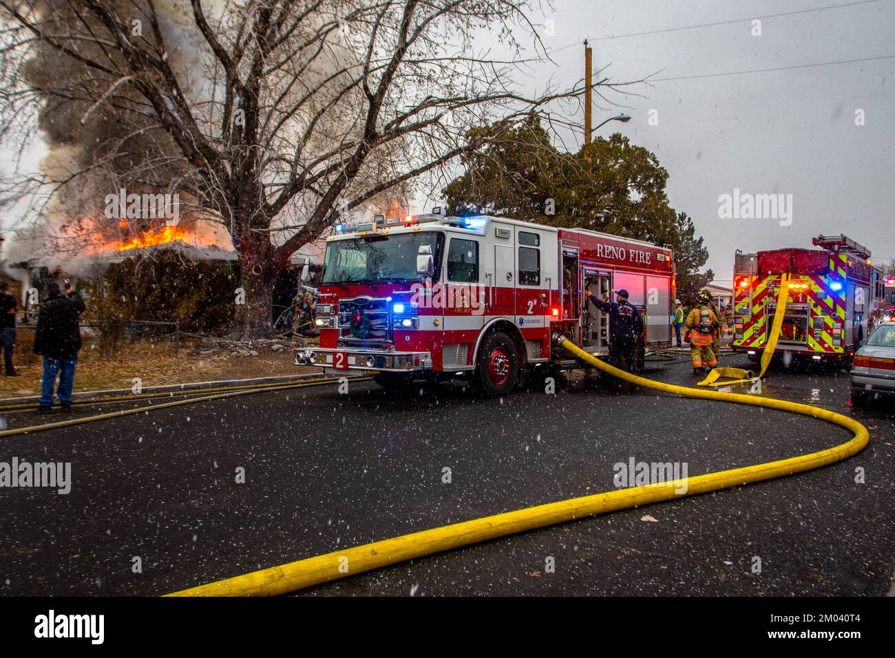 Firefighters work on a structure fire in a snow storm. Two unoccupied ...