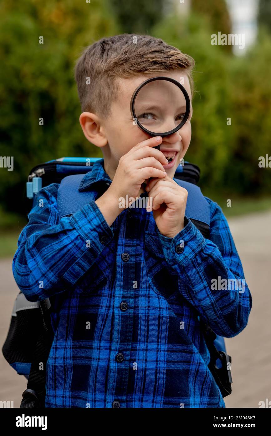 Schoolboy looking through a magnifying glass, with a surprised ...