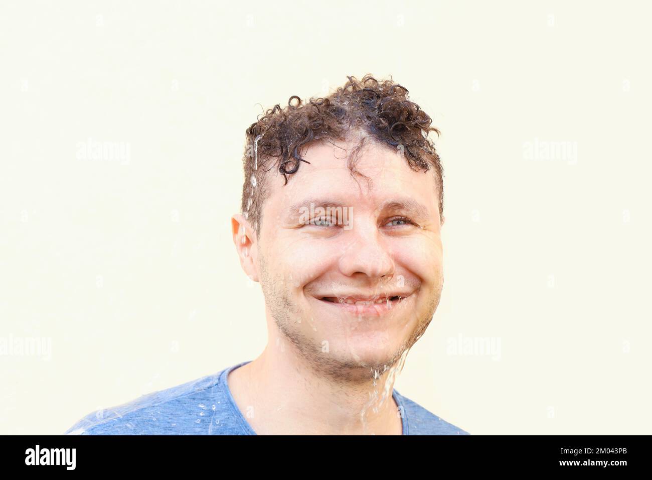 Wet european white young male man with falling jet of water on yellow ...