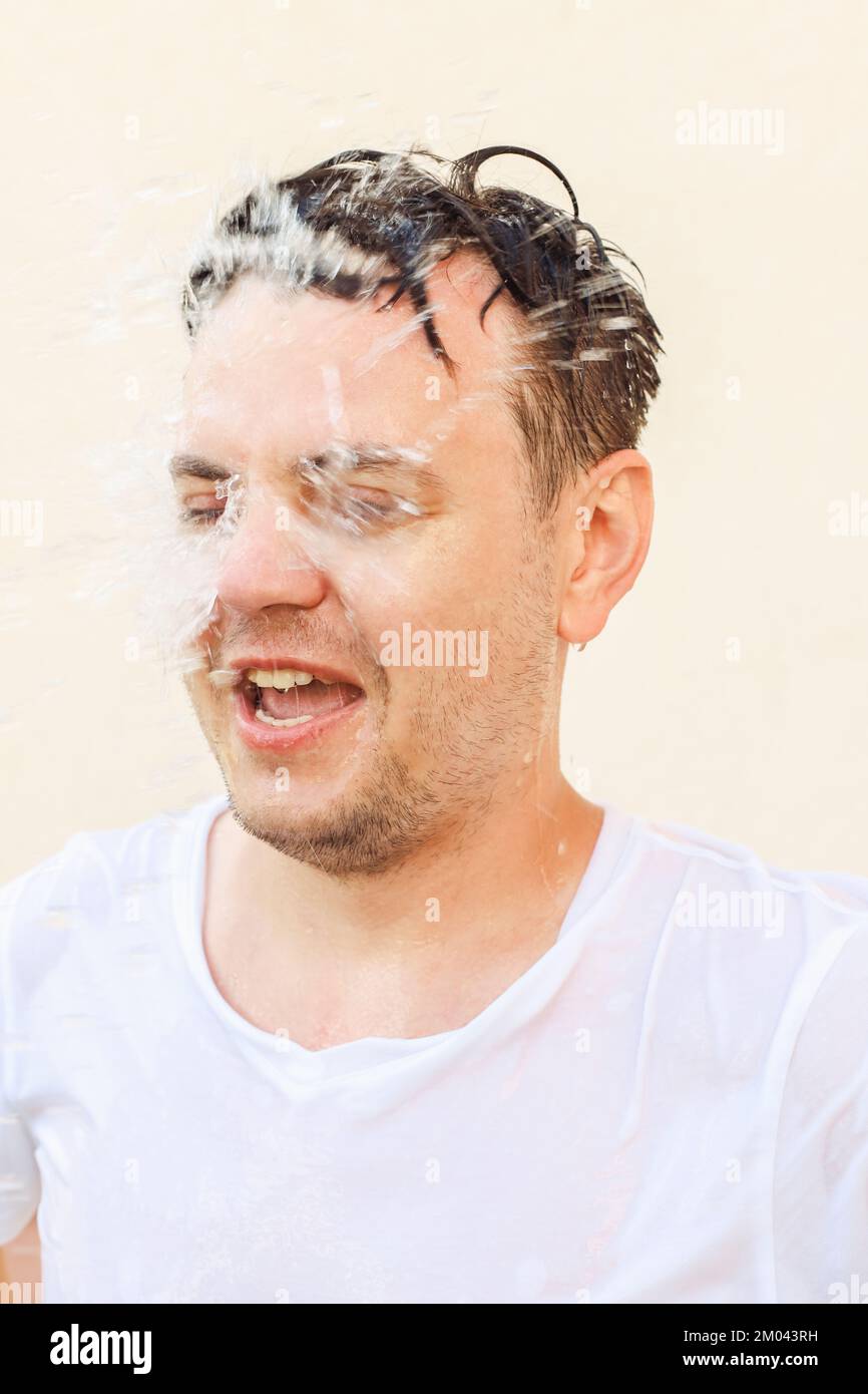 Jet of water, water splash flying in man male face. Shocked young ...