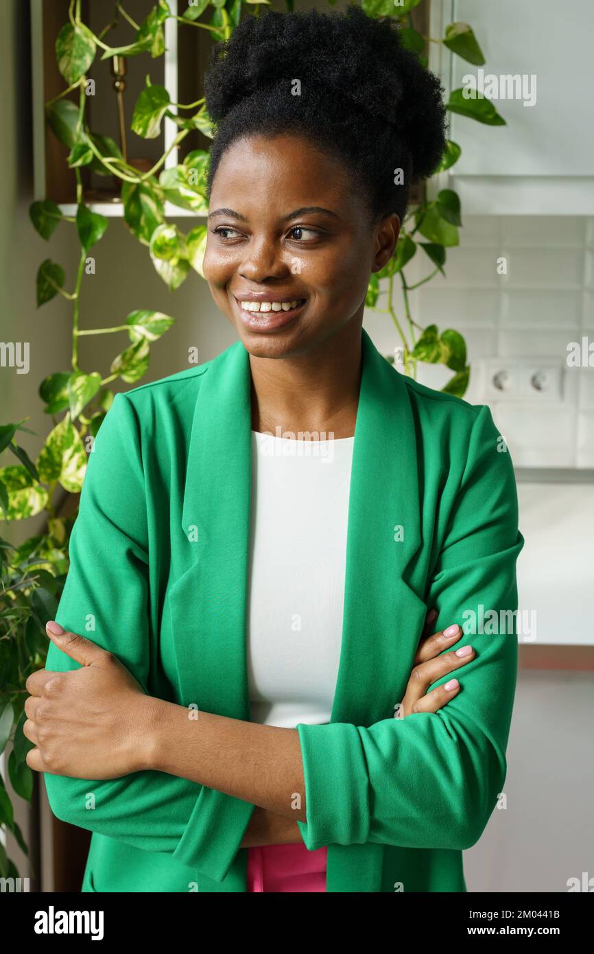 Happy cheerful young African woman looking out of window with smile ...