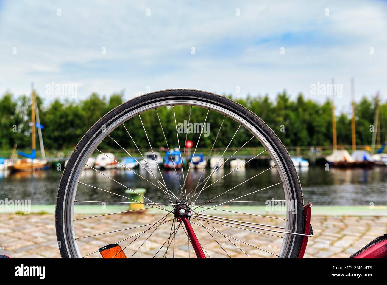 View through the spokes of a bicycle at boats on the river, symbolic ...