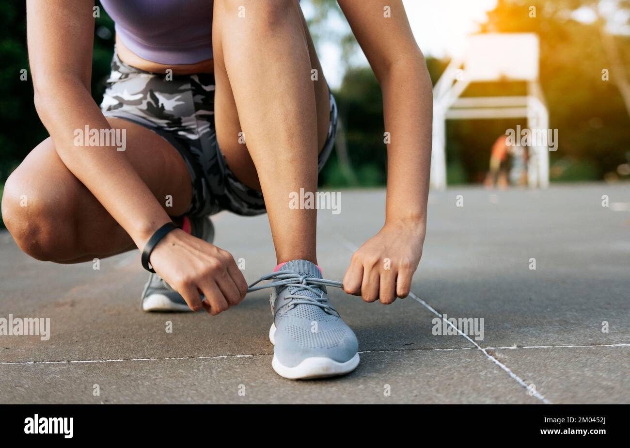 Sport girl tying her shoe laces in a park. Runner girl tying her ...