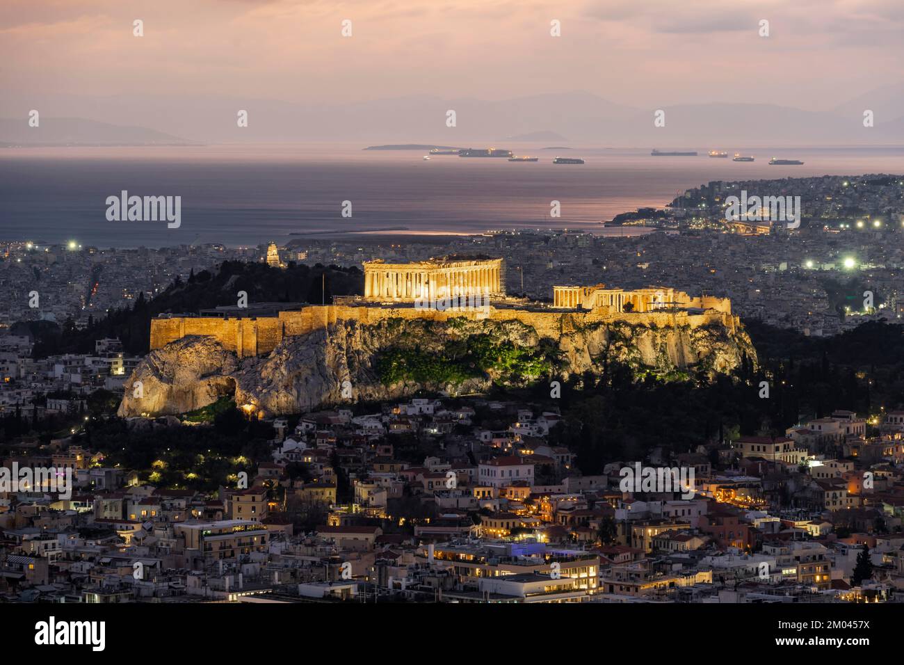 View over the sea of houses of Athens, illuminated Parthenon temple on the Acropolis, from Mount ...