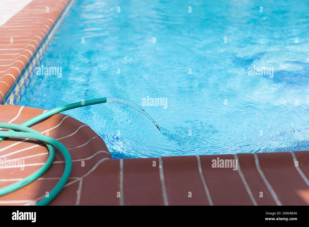 Water pipe filling up swimming pool, closeup. Pool maintenance ...