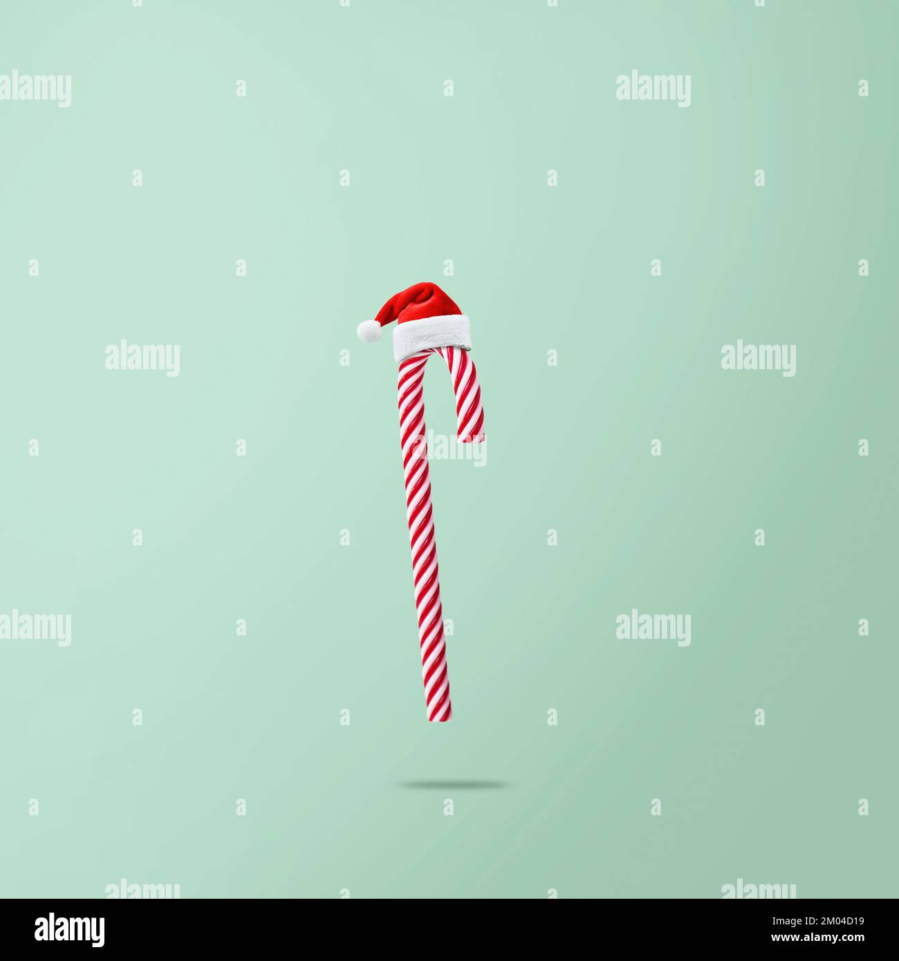 Creative layout of candy cane with Santa's hat on green background ...