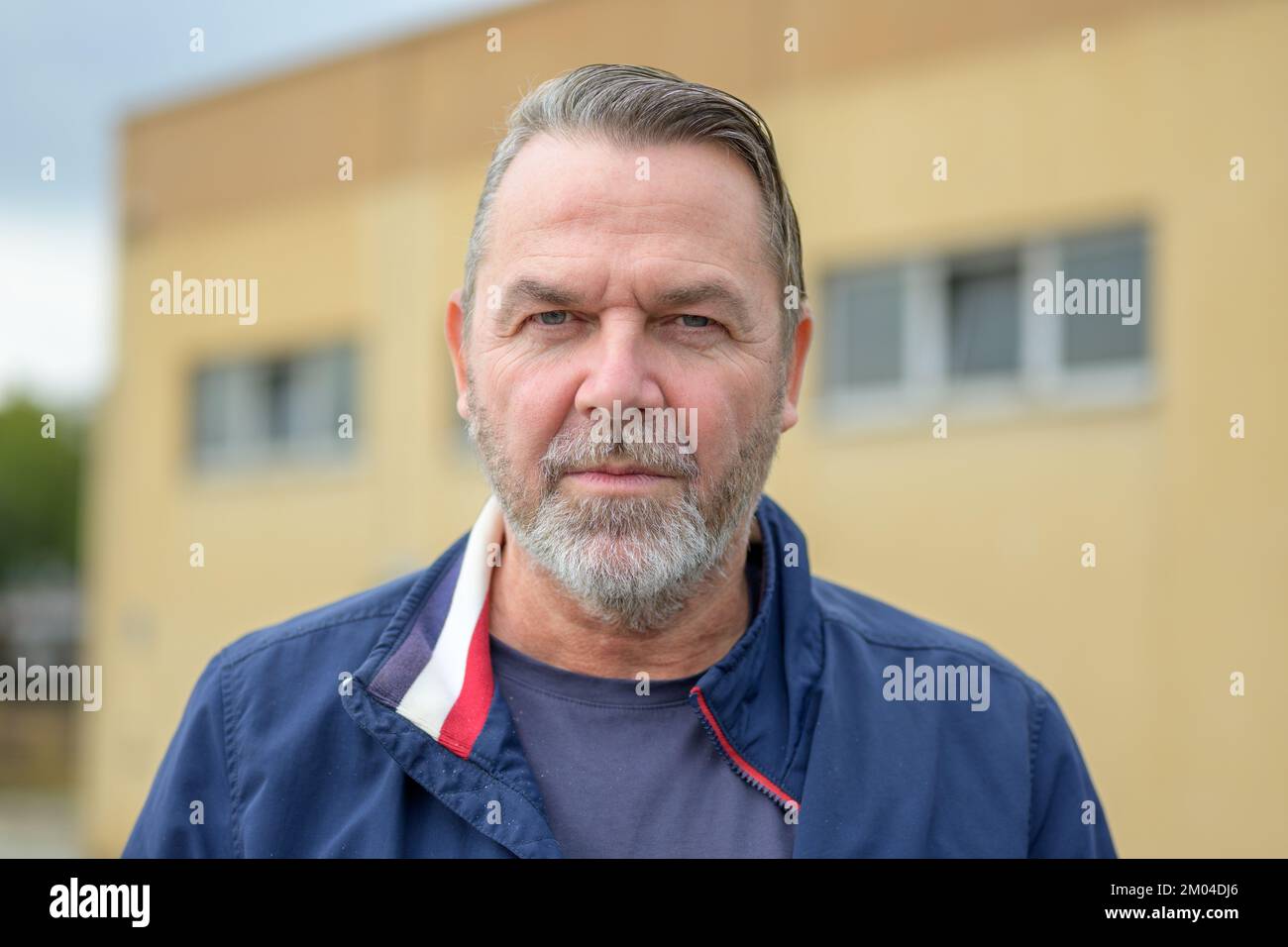 Middle aged man looking at the camera with a stern look outside in ...