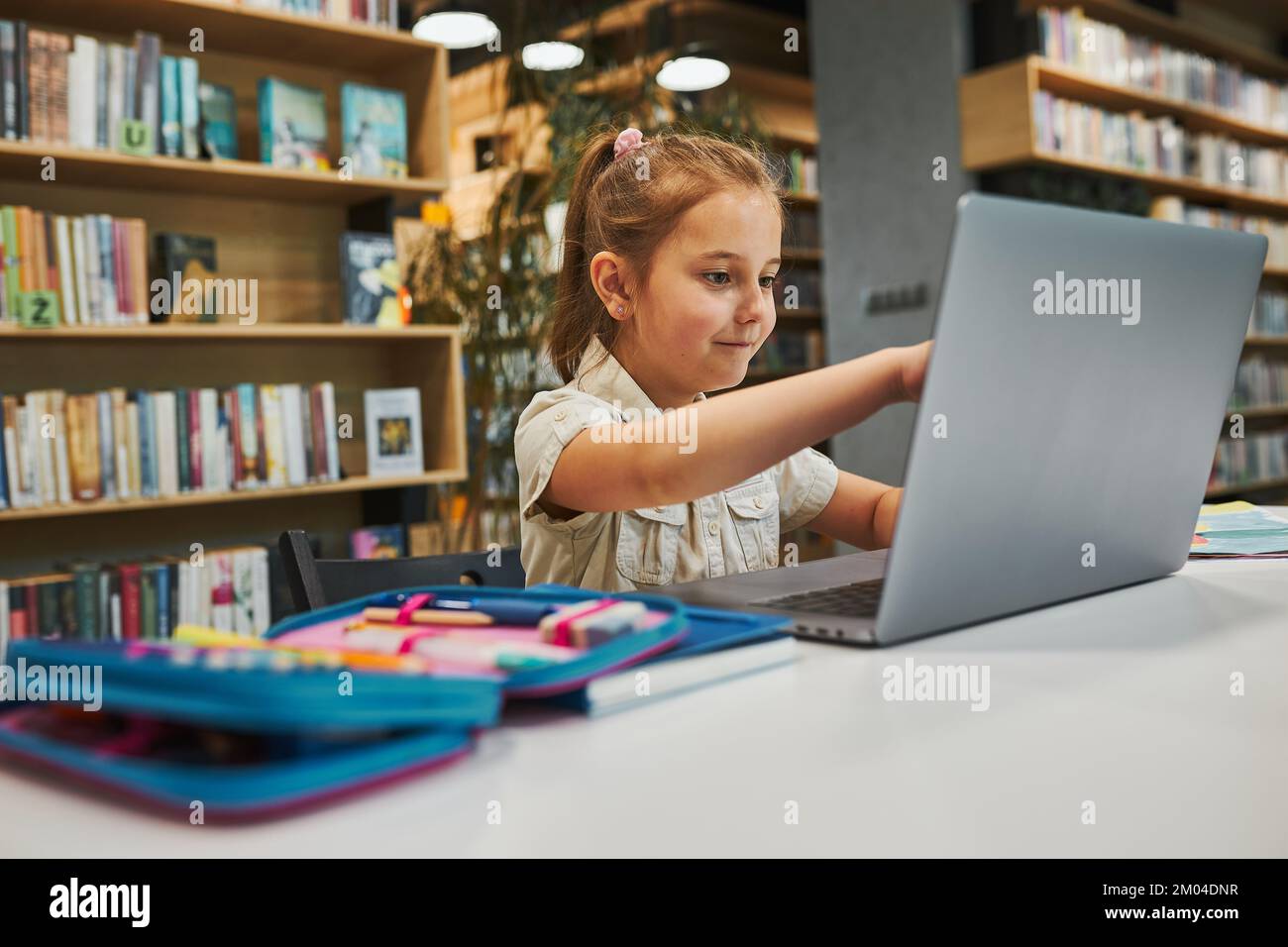 Positively engaged student doing her homework using laptop in after ...