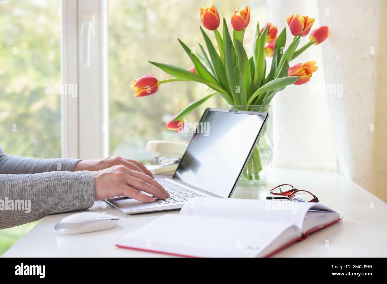 Hands of a woman typing on a laptop computer on a white desk with ...
