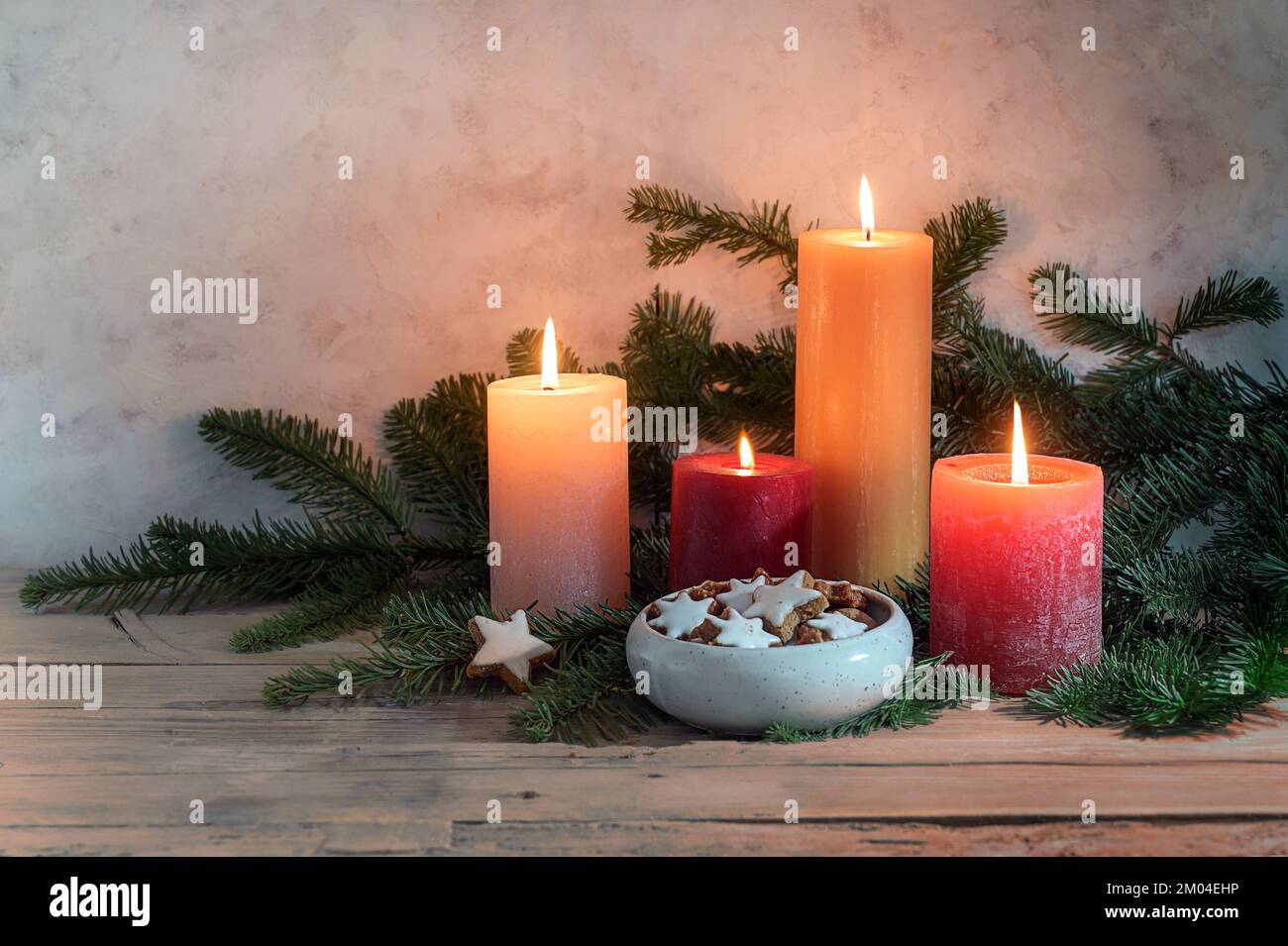 Candles in red orange and cinnamon stars in a bowl on fir branches ...