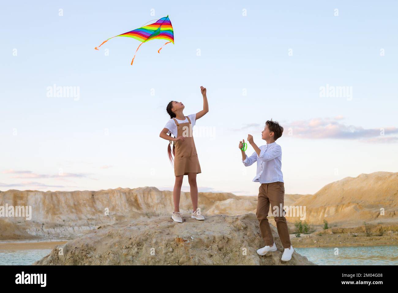 Brother and sister are flying kite standing high on mountain near a ...