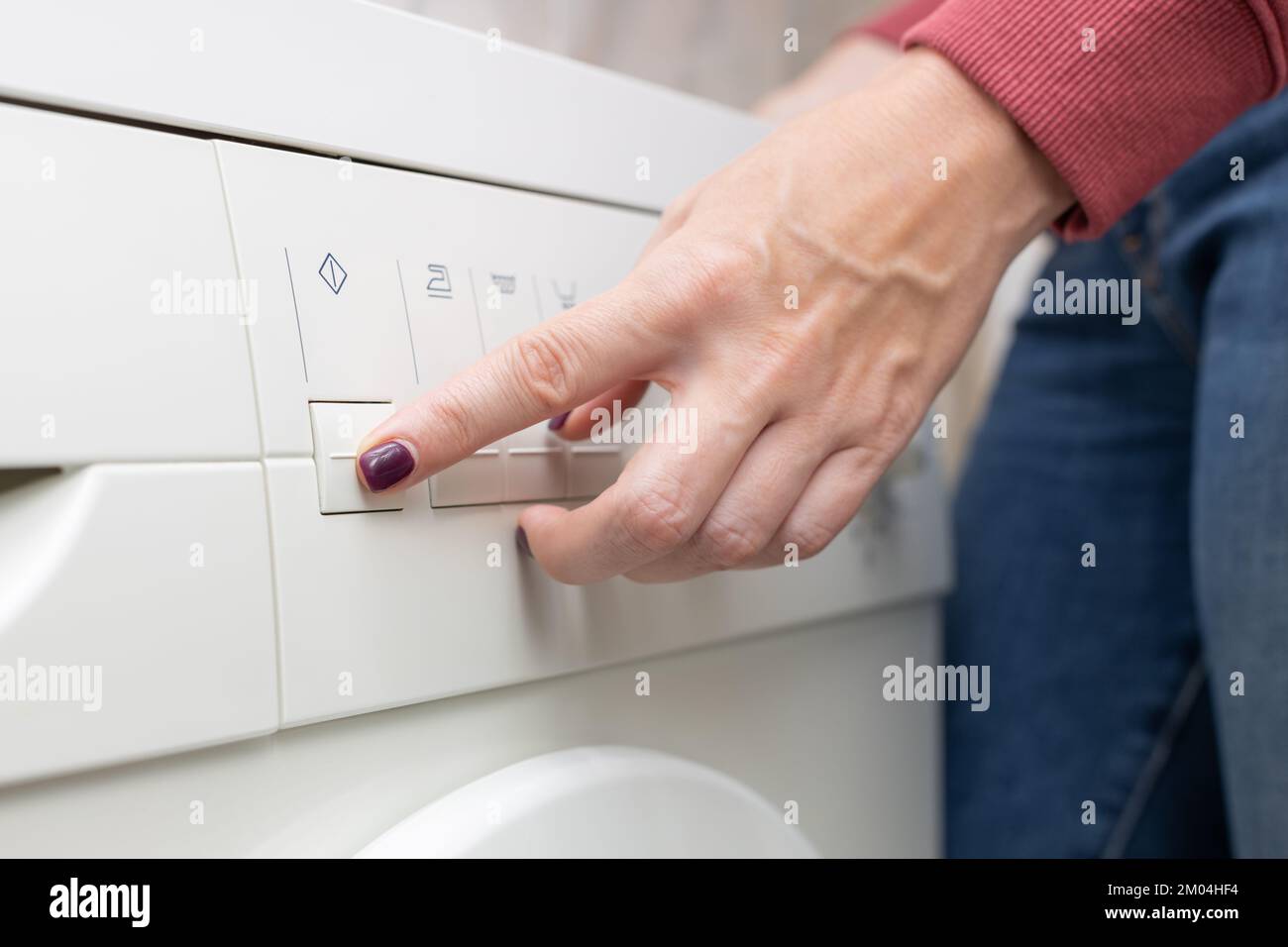 man presses the button on the washing machine Stock Photo - Alamy